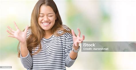 이상의 줄무늬 스웨터를 입고 젊은 아름 다운 갈색 머리 여자 배경 축 제기 및 닫힌 눈 비명 흥분 하는 무기와 성공을 위해 미친 미친 하 고립 우승자 개념 갈색 머리에 대한