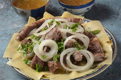 베쉬바르막 고기와 파스타로 준비된 국립 카자흐 요리 베쉬바막 접시가 테이블의 접시에 클로즈업합니다 삶은 고기와 양파의 큰 조각