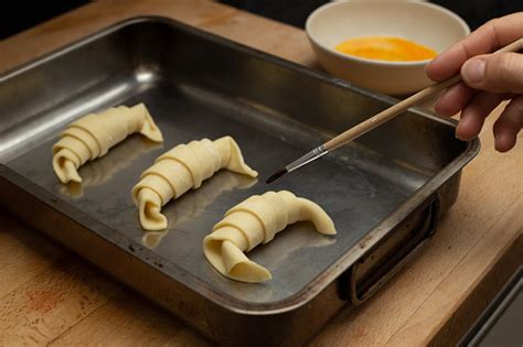 오븐 트레이에 세 개의 원시 크루아상 위에 노른자를 닦는 암컷 손 계란 노른자에 대한 스톡 사진 및 기타 이미지 계란 노른자 곡초류 날것 Istock