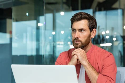 Portrait Of A Young Thoughtful Serious Man Businessman Freelancer Programmer Sitting At A