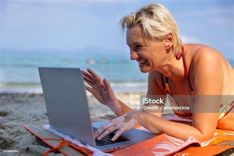 해변에서 일광욕을 하는 동안 노트북으로 화상 통화를 하는 백인 여성 50 54세에 대한 스톡 사진 및 기타 이미지 50 54세 관광객 그리스 Istock