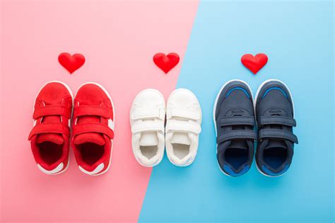밝은 파란색 분홍색 테이블 배경에 어린 아이들을위한 빨간색 흰색과 어두운 파란색 스포츠 신발 위의 심장 모양 파스텔 색상 근접