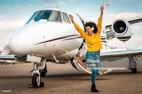 그녀는 공항 활주로에 주차 된 개인 제트기 옆에 헤드폰을 통해 재생 음악을 즐기는 어린 소녀 개인 비행기에 대한 스톡 사진 및 기타 이미지 Istock