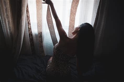 Premium Photo The Girl Sits On The Bed And Opens The Curtains