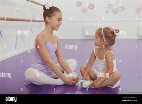 Two Adorable Little Ballerinas Smiling At Each Other Sitting On The