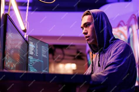 Premium Photo Asian Hacker In Hood Installing Spyware On Victim Computer And Coding Ransomware