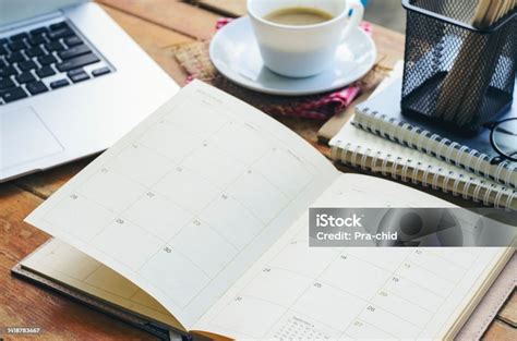 이벤트 플래너가 사무실 테이블에서 시간표 약속 조직 및 관리를 계획하는 일기 일정 및 의제 데스크탑 캘린더와 커피는 나무 책상 위에 놓였습니다 달력 배경 개념 달력에 대한