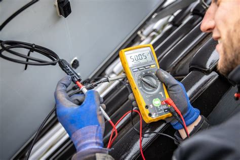 Technician With A Multimeter Testing A Solar Panel On A Roof For Its