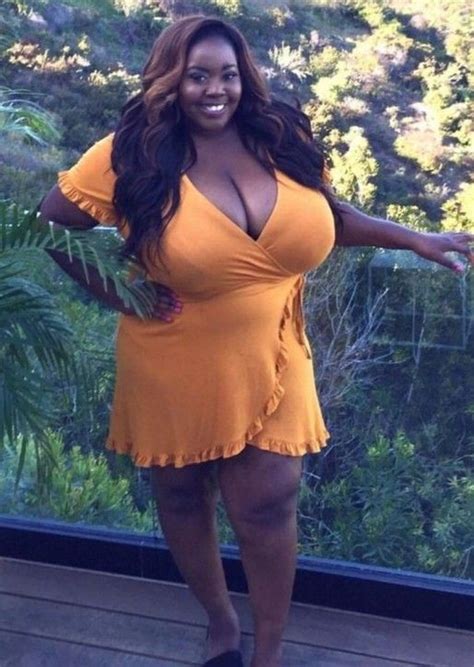 A Woman In A Yellow Dress Standing On A Deck With Her Arms Out And Smiling