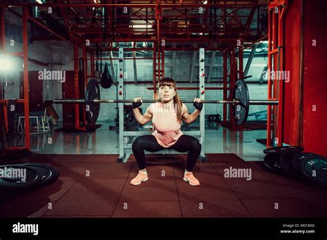 Gorgeous Young Fitness Woman Crouch And Doing Squad Exercise With A Bar