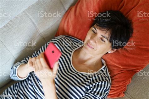 집에서 소파에 누워있는 스마트 폰에서 소셜 네트워크를 확인하는 여성 50 54세에 대한 스톡 사진 및 기타 이미지 50 54세 스마트폰 여자 Istock