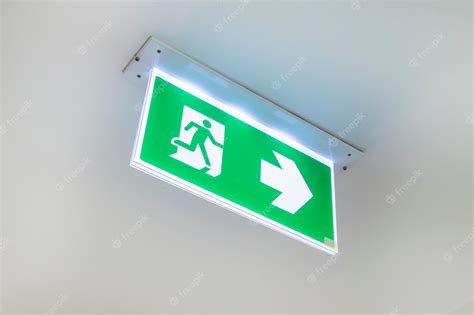 Дверь аварийного выхода на потолке зеленый знак аварийного выхода показывая путь Премиум Фото