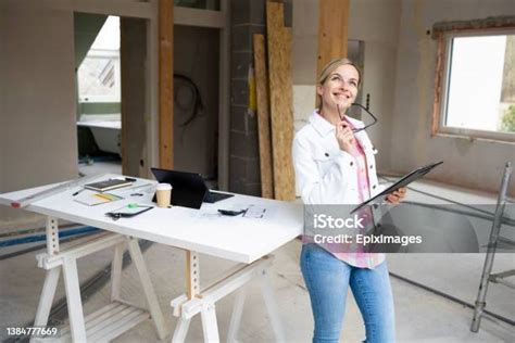 로프트의 건설 현장에서 일하는 예쁜 젊은 건축가와 컬러풀한 셔츠와 청바지 바지가있는 높은 테이블 옆에 서 있습니다 40 44세에 대한 스톡 사진 및 기타 이미지 Istock