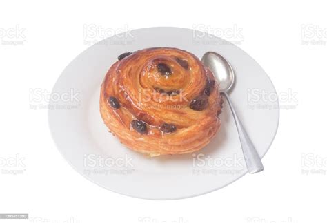 나선형 덴마크 패스트리 또는 하얀 접시 위에 건포도가 든 달콤한 롤빵과 작은 찻 숟가락이 흰색 배경에 고립 된 아침 식사를 제공합니다 0명에 대한 스톡 사진 및 기타 이미지