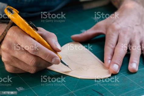 소의 피부에 커터 슬릿을 사용하는 클로즈업 손 신발을 만드는 데 사용하기 위해 가죽의 패터닝을 위한 또 다른 단계이며 장인은 손으로 소가죽을 꼼꼼하게 자르고 있습니다 40