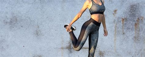 Uma Garota Magra Esportiva Em Leggings E Um Top Está De Pé Contra Uma