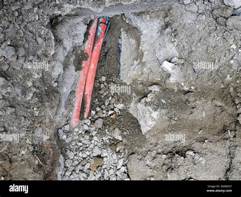 Utility Lines Exposed During Excavation In A Construction Site Revealing Red And Blue Cables