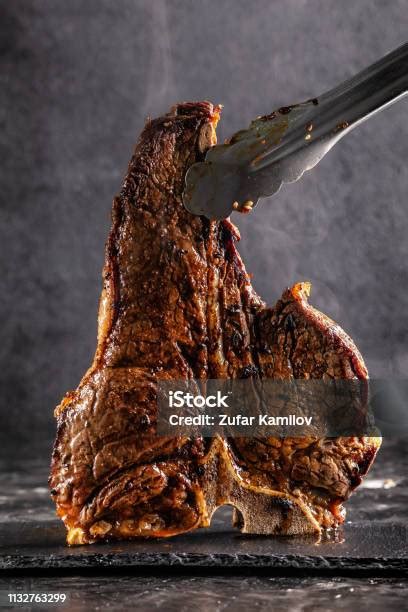 연기가 나는 큰 쇠고기 로스트 티 본 스테이크 검은 배경에 스테이크 고기 집게를 들고 머리 요리사 광자 이미지 복사 공간 스테이크에 대한 스톡 사진 및 기타 이미지 Istock