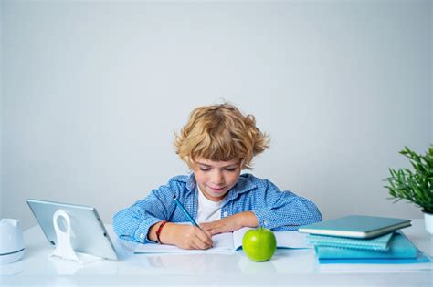 초등학교 소년 소녀는 책상에 앉아 알파벳을 공부하고 편지 책과 태블릿을 공부하고 교실에서 카메라를 보고 있다 빈 개념을 광고하기 위한 공간을 복사합니다 학교로 돌아 가기