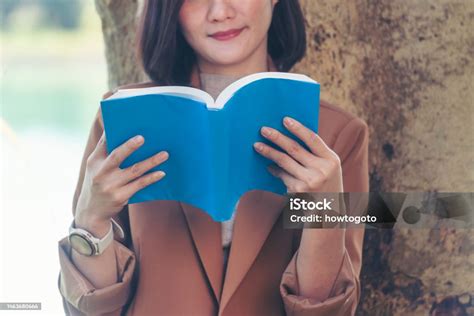 녹색 공원 자연에서 야외에서 책을 읽는 행복한 아시아 여성 독서 책 잡지 휴식 여자 녹색 공원에 앉아있는 레저 초상화 여성 미소 행복한 얼굴로 전자 책 일기 플래너를