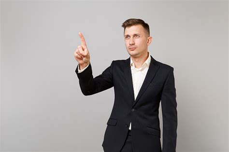 젊은 비즈니스 맨 터치 푸시 같은 부동 회색 벽 배경에 고립 된 가상 화면에서 가리키는 버튼 클릭 합니다 성과 경력 부 비즈니스 개념입니다 복사 공간을 비웃는 다 검은색에