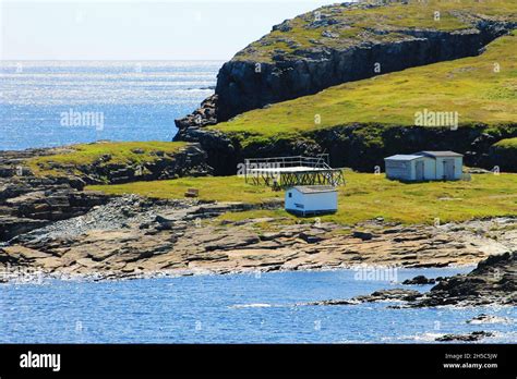 A Fishing Stage And Fishing Sheds On A Grassy Hill Next To The