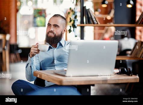 Young Serious Bearded Businessman Working On Computer At Table Drinking Coffee Man Analyzes