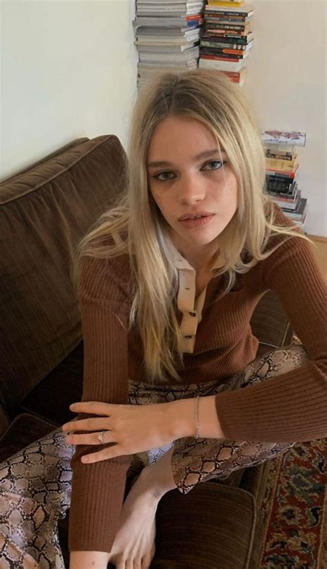 A Woman Sitting On Top Of A Couch Next To A Pile Of Books