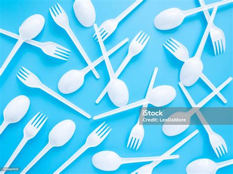 일회용 식기 흰색 플라스틱 포크와 숟가락은 파란색 배경 상단보기 평평한 평신도에 흩어져 있습니다 플라스틱 제품의 생태 및 재활용에 대한 배경 디자이너의 레이아웃 또는 공백