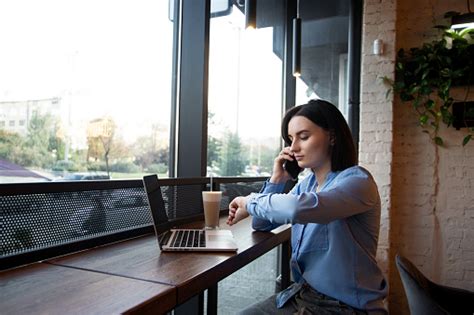 바쁜 프리랜서 여성은 자신의 시계를보고 고객과 뭔가를 논의 원격 작업 개념 배경에 카페 또는 레스토랑 작은 시간 개념 맛있는 라떼 컵 20 24세에 대한 스톡 사진 및 기타