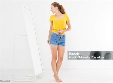 소녀는 옷을 입고 거울을 보고 옷을 입어보십시오 쇼핑 및 체중 감량 개념 공간을 복사합니다 빈 템플릿 배경입니다 좋은 체형과 여름 다이어트 옷가게 탈의실에 대한 스톡 사진