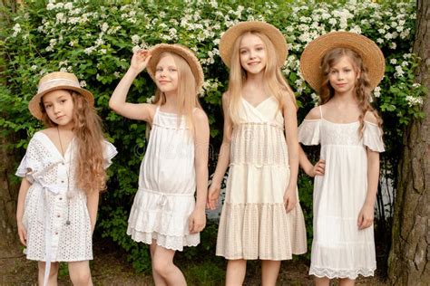 Cheerful Tween Girls Posing In Green Garden Near Flowering Shrub Stock