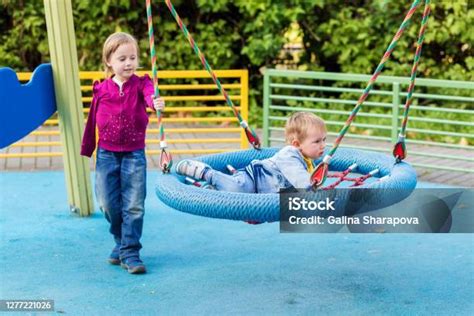 여동생은 놀이터에서 스윙에 그녀의 동생을 스윙 소녀는 부러진 팔을 가지고있다 2 3 살에 대한 스톡 사진 및 기타 이미지 2