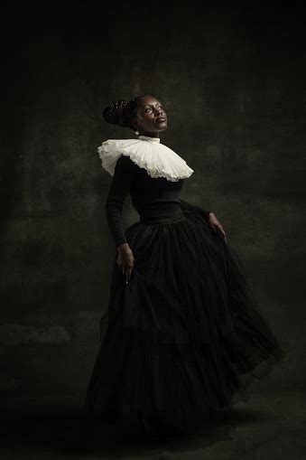 짙은 녹색 배경에 고립 된 포즈 큰 흰색 칼라와 검은 빈티지 드레스를 입고 중세 아프리카 젊은 여성 시대 현대성 르네상스의 비교 개념 인물 사진에 대한 스톡 사진 및 기타
