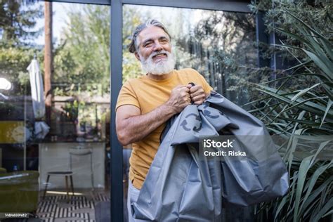재활용을 위해 쓰레기로 가득 찬 쓰레기 봉투 두 개를 들고 다니는 성인 남성 50 54세에 대한 스톡 사진 및 기타 이미지 50 54세 55 59세 가정 생활