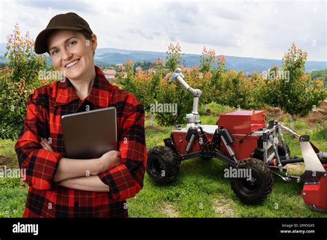 Farmer Controls Autonomous Robot In A Fruit Garden Smart Farming Concept Stock Photo Alamy