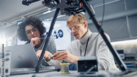 Black Professional Female Developer Coding On Laptop While Her Young Male Colleague Holding