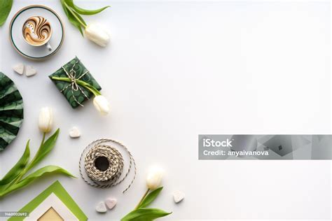 장식 테두리 흰색 튤립 꽃 커피 컵 및 선물 상자 녹색 포장지 가위 및 코드가 있는 흰색 배경 플랫 레이 평면도 오버 헤드 복사 공간 텍스트 배치 꼭대기에 대한 스톡 사진