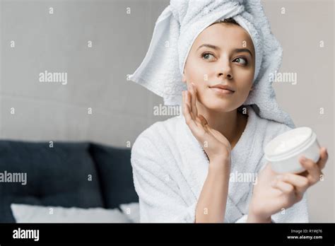 Beautiful Girl With Towel On Head Applying Cosmetic Cream On Face Stock