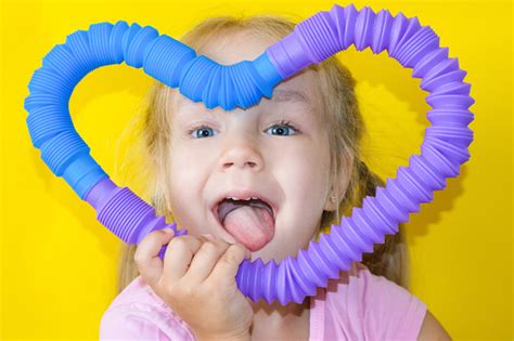 팝 튜브 아이의 손에 팝 튜브에서 안티 스트레스 감각 플라스틱 장난감 장난감 안절부절 팝 튜브와 함께 재생 쾌활한 어린 소녀 2021년 의 추세 배관에 대한 스톡 사진 및