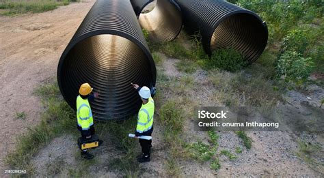 두 명의 젊은 건설 엔지니어가 교외에 새로운 도로 시스템을 구축하기 위해 운송하기 전에 작업 현장을 조사하고 대형 배수관 자재를 검사하는 조감도 2명에 대한 스톡 사진 및