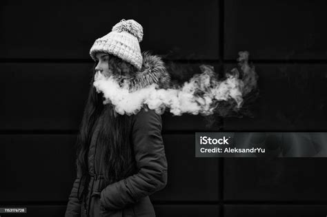 Vape 십 대 젊은 예쁜 백인 소녀 겨울 거리에 현대 배경 맞은편 전자 담배를 흡연 나쁜 습관 18 19세에 대한 스톡 사진 및 기타 이미지 Istock