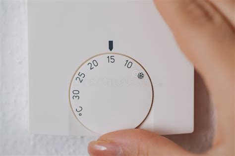 Female Hand Turns On Central Heating Thermostat Control Dial Adjustment Stops At 15 Degree