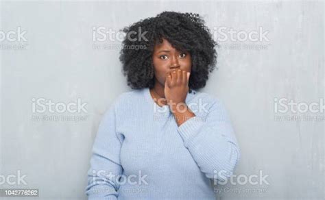 강조 하 고 손톱을 물어 뜯고 입에 손을 긴장을 찾고 겨울 스웨터를 입고 회색 그런 지 벽에 젊은 아프리카계 미국인 여자 불안 문제입니다 무서움에 대한 스톡 사진 및 기타