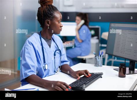 african american nurse working at desk inserting data in appointment