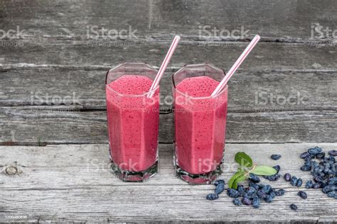 오래된 회색 나무 배경에 신선한 야생 허니 서클과 녹색 잎과 어두운 파란색 열매에서 마시는 스무디와 플라스틱 튜브와 두 개의 투명 안경 가막살나무에 대한 스톡 사진 및 기타