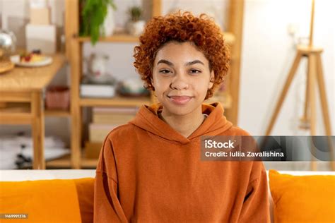 아프리카 헤어스타일을 한 아름다운 아프리카계 미국인 소녀가 집 실내 소파에 앉아 웃고 있다 곱슬머리를 한 젊은 아프리카 여자가 웃고 있다 자유 행복 평온 행복한 사람들의