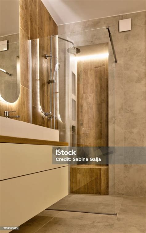 세라믹 욕실 세면대 조명 효과가 있는 원형 거울 유리가 있는 샤워기가 있는 현대적인 욕실의 홈 인테리어 새 아파트의 우아함과