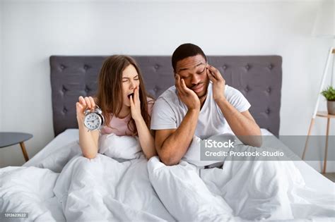 인종 간 결혼 한 부부는 아침에 깨어있는 데 문제가 알람 시계와 침대에 졸린 앉아 2명에 대한 스톡 사진 및 기타 이미지 2명 가정 생활 가족 Istock