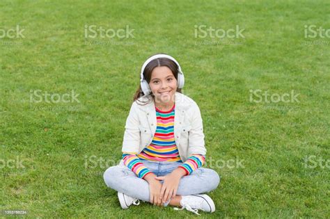 평온한 느낌 헤드폰에 작은 아이 여름 재생 목록 야외에서 봄의 자연을 즐기십시오 어린이 학습 오디오 북 새로운 기술 아이는 잔디에서 음악을 듣습니다 건강한 라이프 스타일과